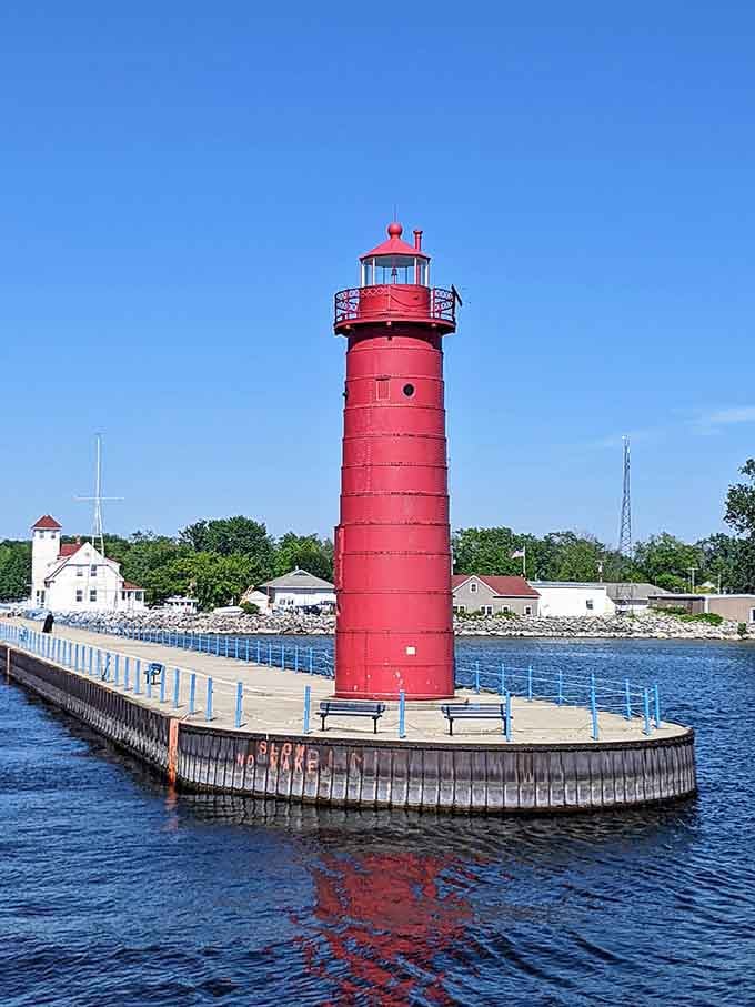 Standing tall on its circular platform, this red tower reflects perfectly in the calm water below.