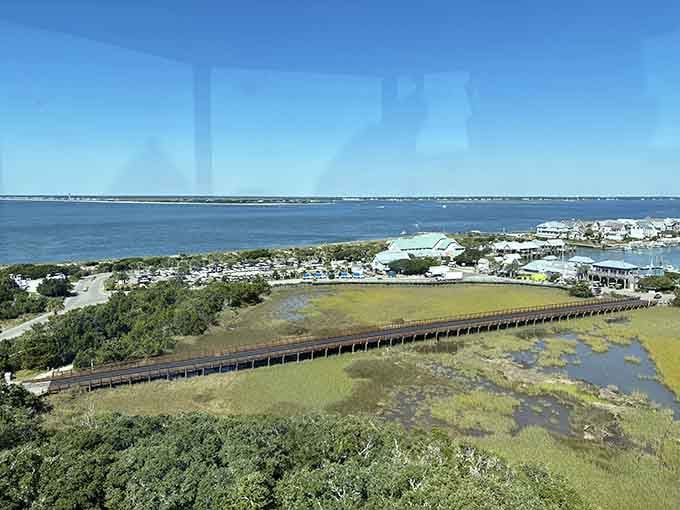 Marshland boardwalks stretch toward sparkling water under endless sky, connecting island life to the rhythm of coastal tides.