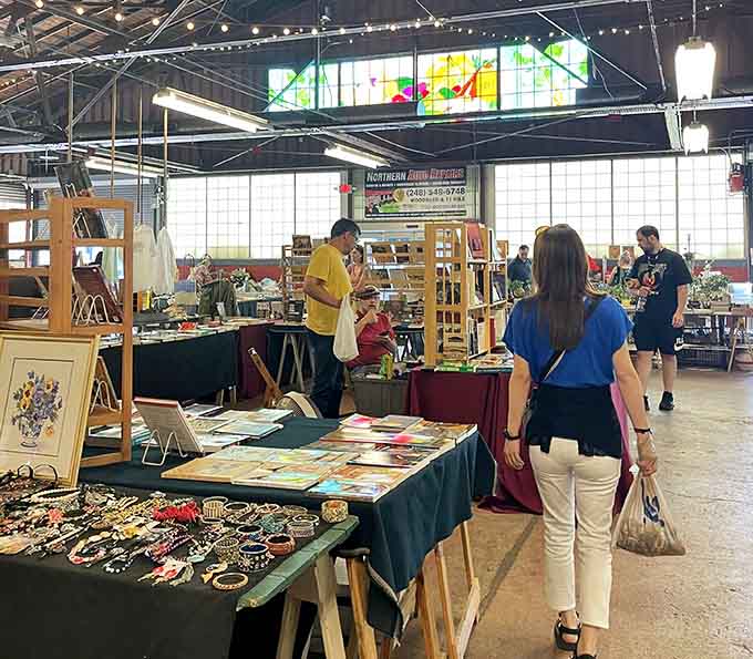 String lights twinkle above vendor booths where shoppers browse handcrafted items and vintage finds in this bright, welcoming indoor space.