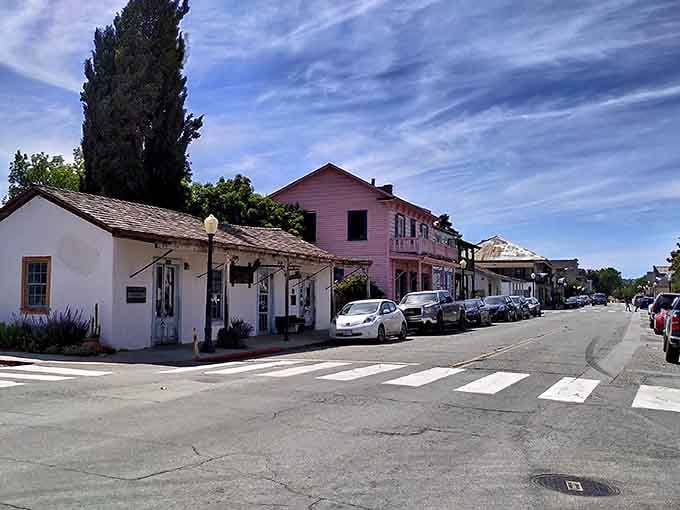 Pink building and parked cars create an unexpected California combination where mission-era architecture meets modern small-town life beautifully.