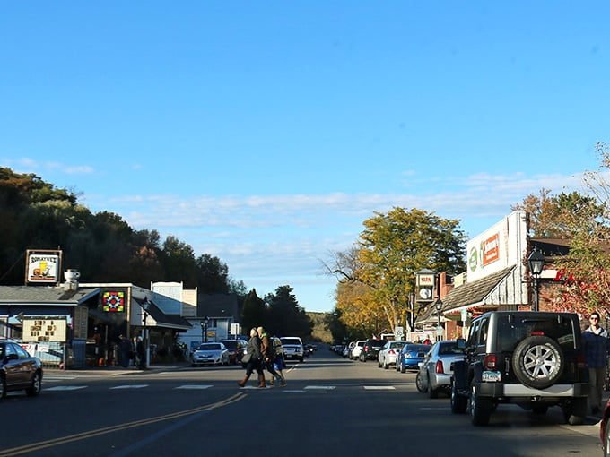 Golden autumn light bathes the street as locals and visitors mingle in this scenic river valley town.