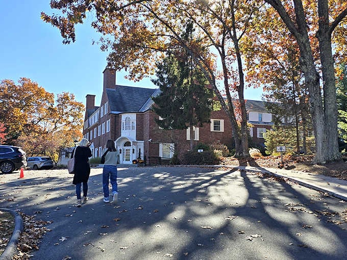 Golden autumn light filters through mature trees, creating long shadows that add drama to this historic inn.
