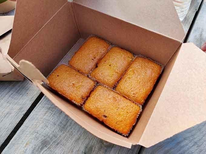 Golden cornbread squares nestled in their box represent the perfect supporting actor to all that starring-role smoked meat.
