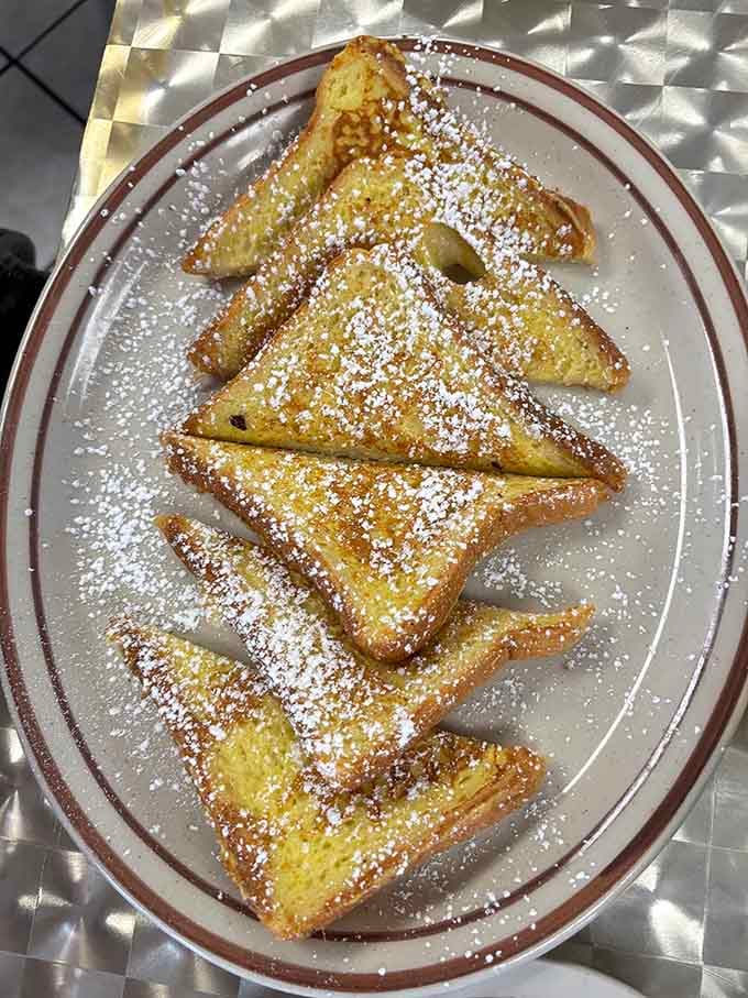 French toast dusted with powdered sugar like fresh snow on a delicious, golden mountain range of carbs.
