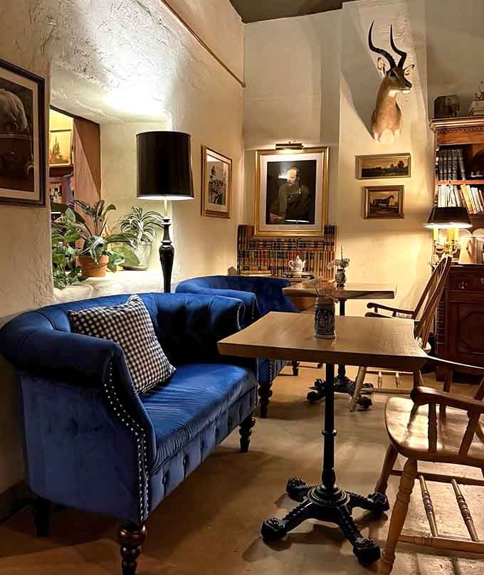 Plush blue velvet seating beneath vintage portraits and that magnificent elk creates an atmosphere worthy of Narnia itself.