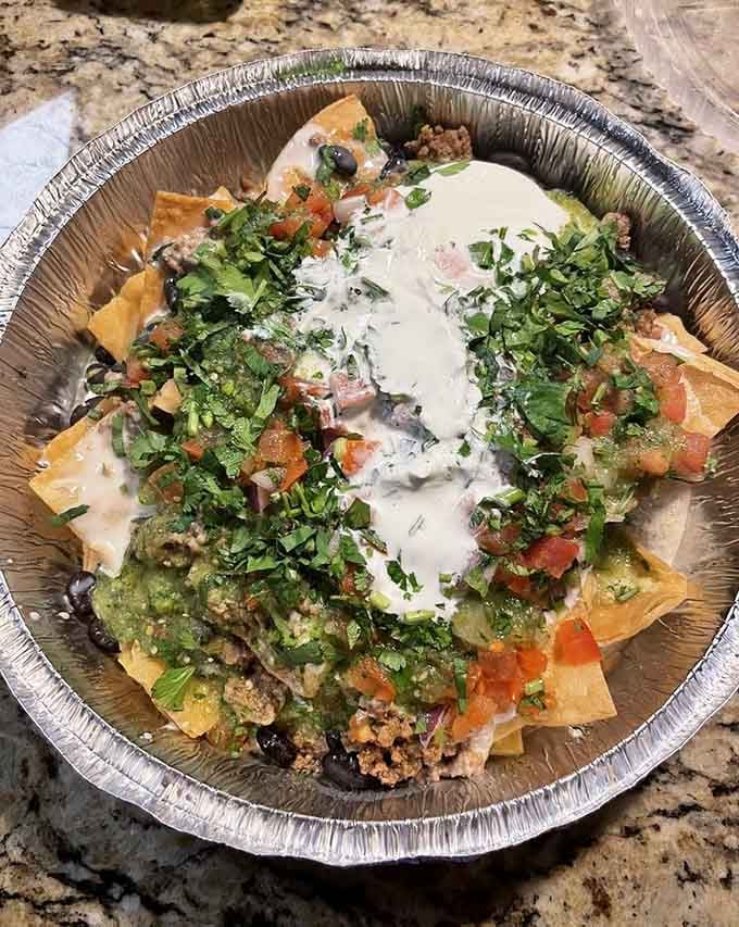 Nachos loaded with toppings from edge to edge, solving the age-old problem of naked chips at the bottom.