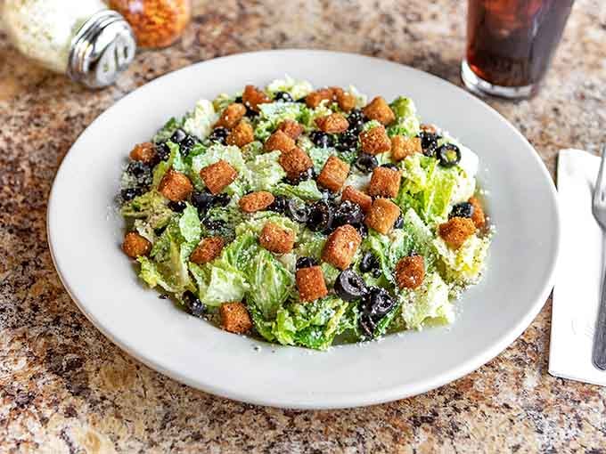 Caesar salad with croutons and olives: the appetizer that lets you pretend you're being healthy before the main event.