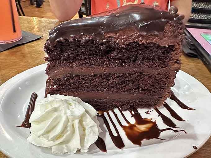 Chocolate cake towering like a delicious skyscraper, engineered specifically to make your diet start tomorrow instead of today.