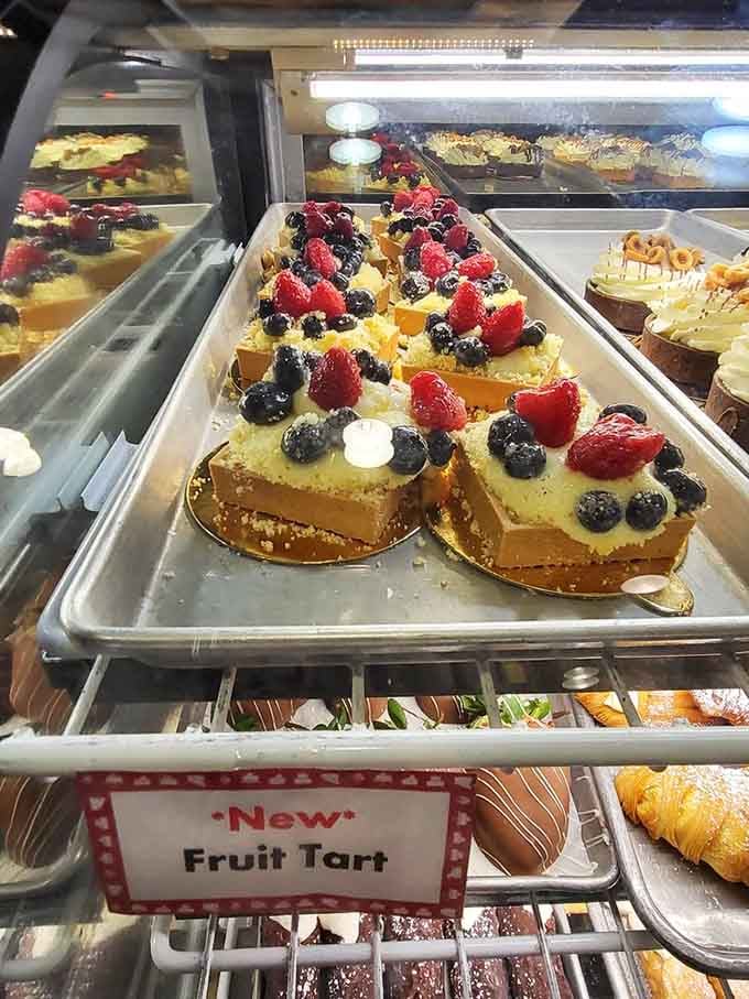 Fruit tarts gleaming like edible jewelry in the display case, their berries arranged with the precision of a master craftsman.