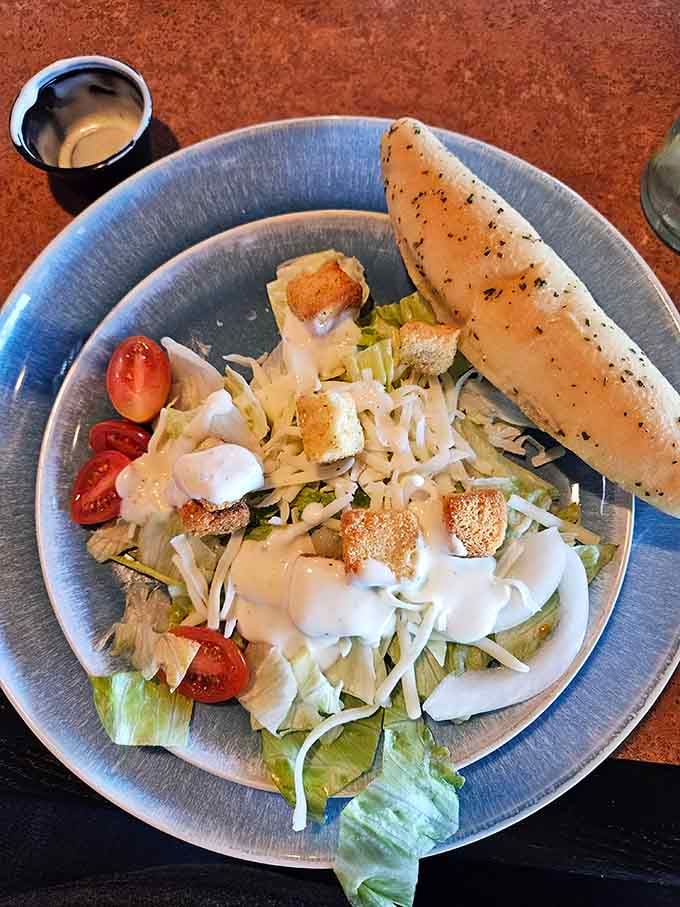 Fresh Caesar salad with garlic bread standing at attention, ready to provide balance before the indulgence continues.