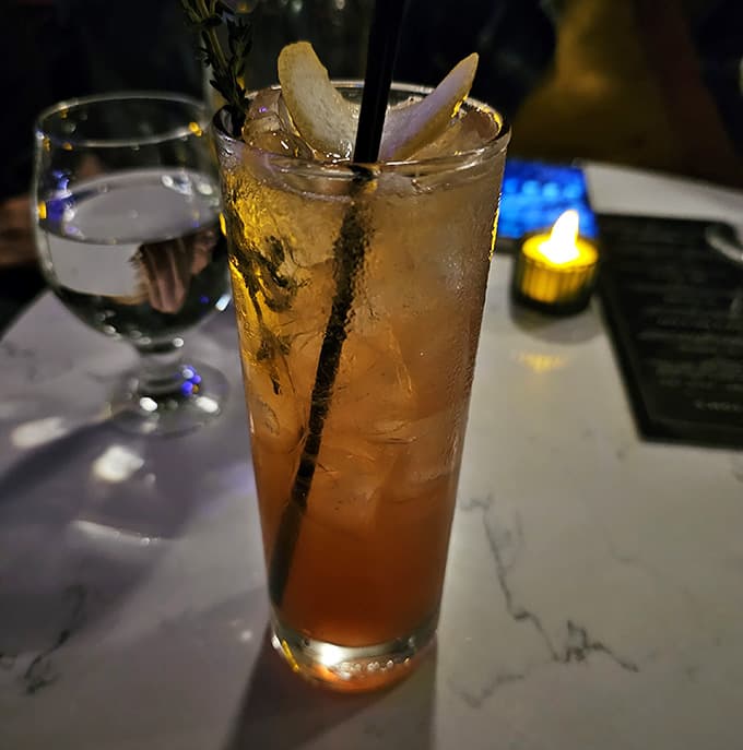 That tall glass of golden refreshment with apple garnish looks like summer decided to stick around for one more round.