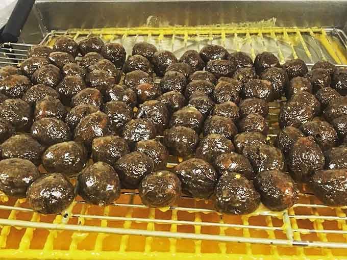 Chocolate donut holes glistening like tiny edible jewels fresh from the fryer and ready to disappear fast.