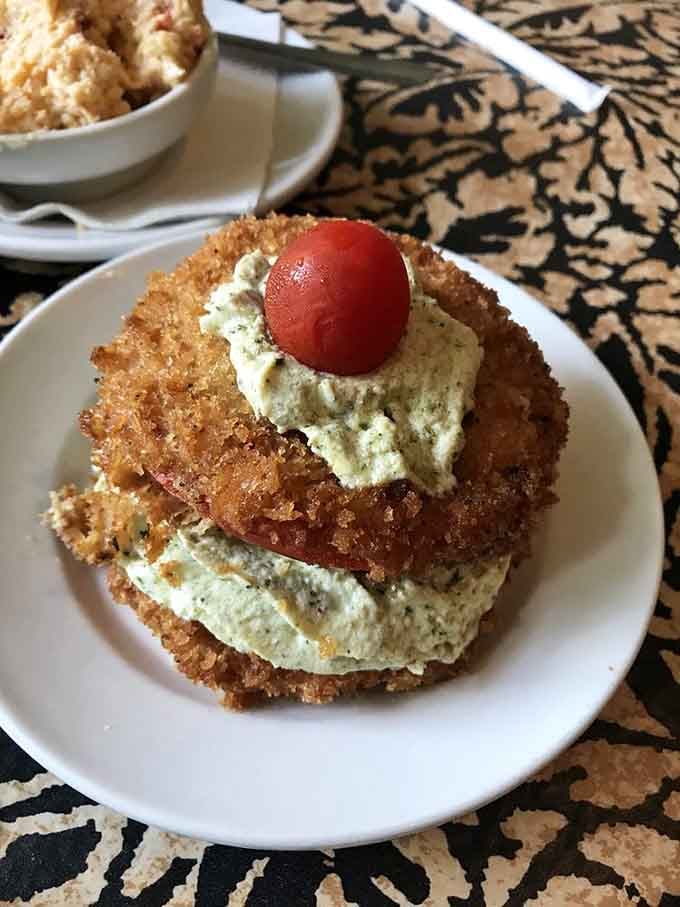 Fried green tomatoes stacked with pimento cheese create a tower of Southern comfort that defies architectural logic.