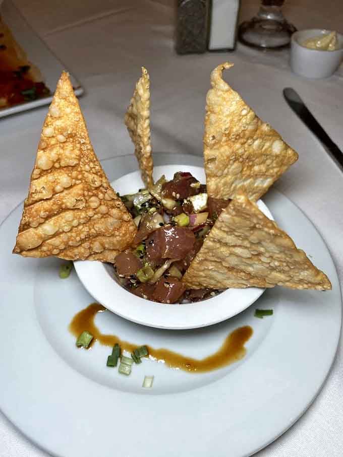 Tuna tartar presented with sesame crisps standing at attention like delicious edible soldiers guarding precious cargo below.