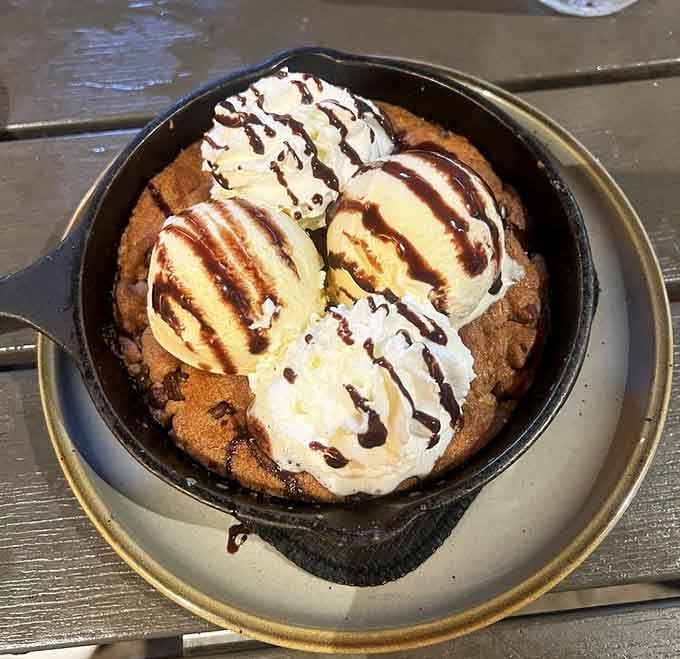 Warm chocolate chip cookie skillet with ice cream melting on top, defeating any remaining willpower you had left.