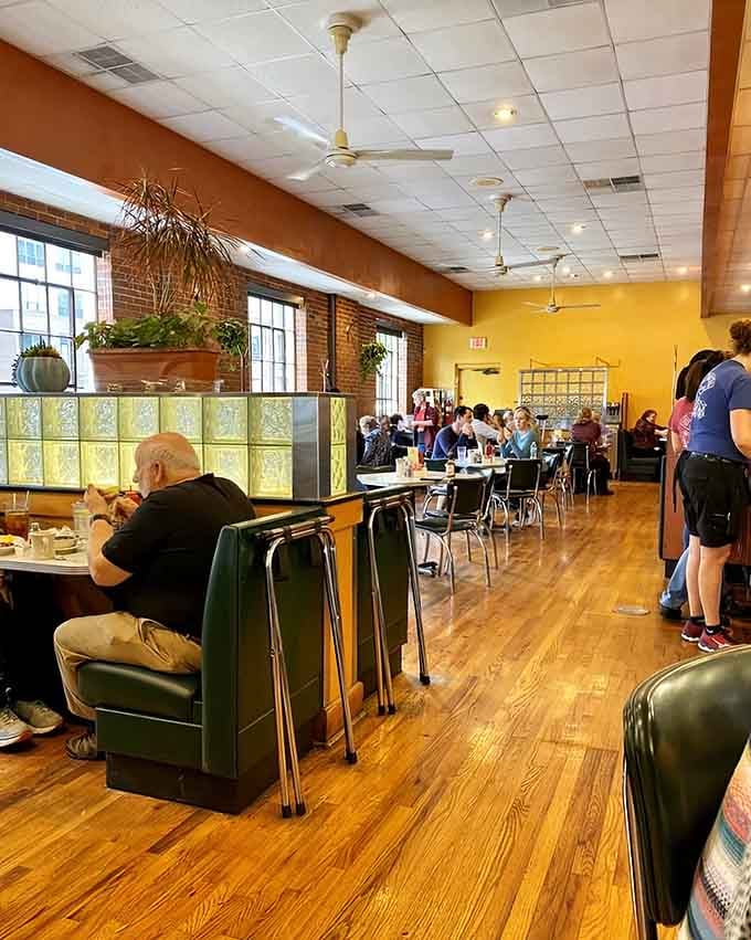 Glass block dividers and warm lighting create cozy dining spaces where conversations flow as freely as the coffee refills.