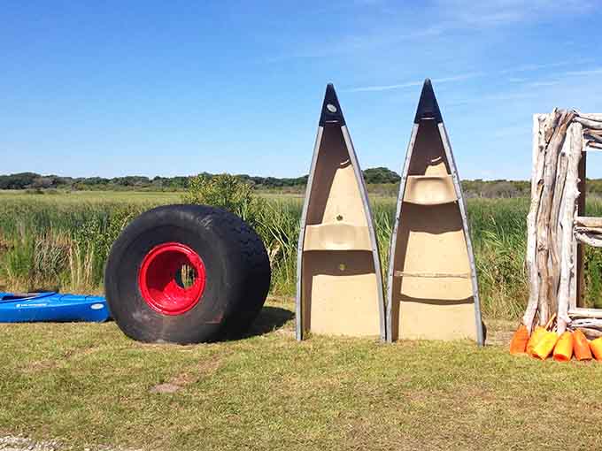 Canoes and oversized tires create an oddly artistic display that screams "beach life" louder than any motivational poster ever could.