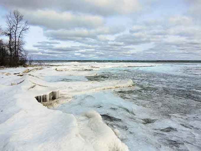 Winter transforms the shoreline into a frozen wonderland that looks like Narnia decided to vacation in northern Michigan.
