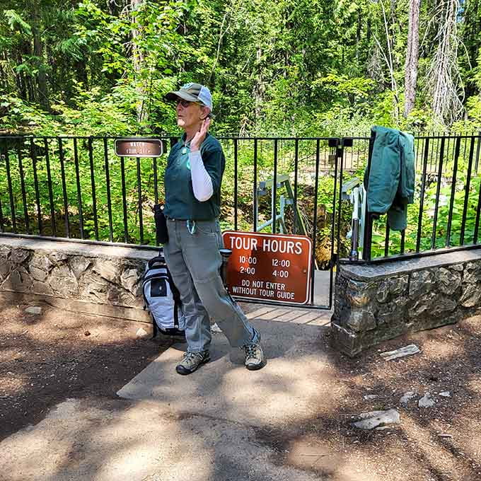 Your friendly park ranger stands ready to guide visitors into the cool depths where geology becomes pure magic.