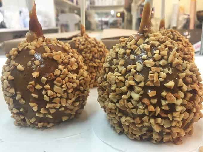 Candy apples coated in chocolate and nuts, shiny and tempting like edible jewels in a display case.