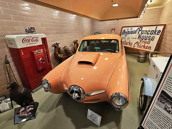 This peachy Studebaker Starlight sits beside vintage Coca-Cola memorabilia, creating the perfect 1950s time capsule vibe.