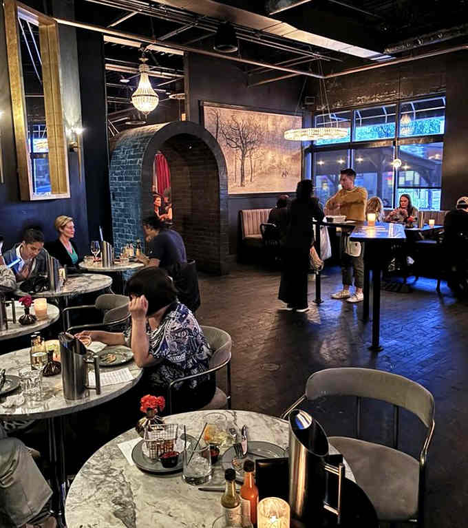 Diners enjoying the intimate atmosphere where chandeliers cast flattering light and conversations flow as smoothly as the cocktails.