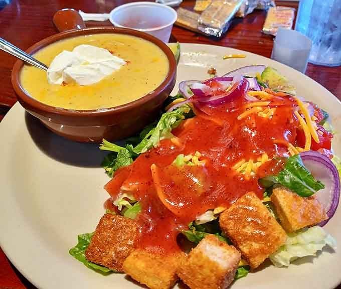 Fresh salad with crispy croutons next to a bowl of golden soup offers comfort in its most wholesome form.