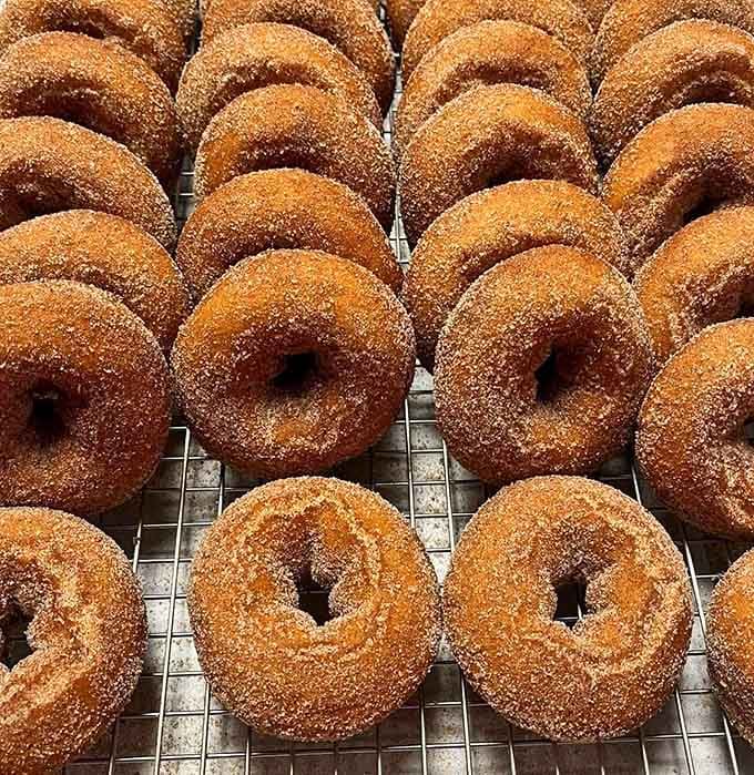 Fresh cinnamon-sugar donuts cooling on the rack, still warm enough to make your willpower completely evaporate into thin air.