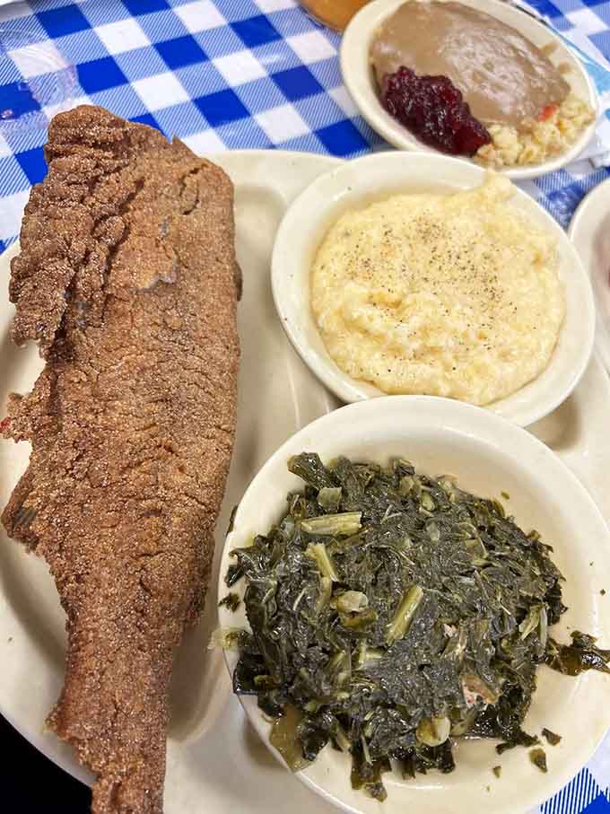 That whole fried catfish stretches across the plate like it's trying to escape, surrounded by sides that complete this perfect Southern symphony.