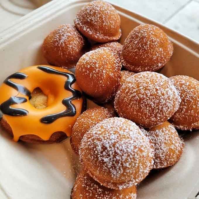 Sugar-dusted donut holes piled high next to a Halloween-themed mochi donut, proving every season deserves its own celebration here.