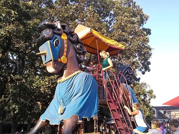 This magnificent rocking horse towers over delighted riders experiencing childhood joy at epic proportions.