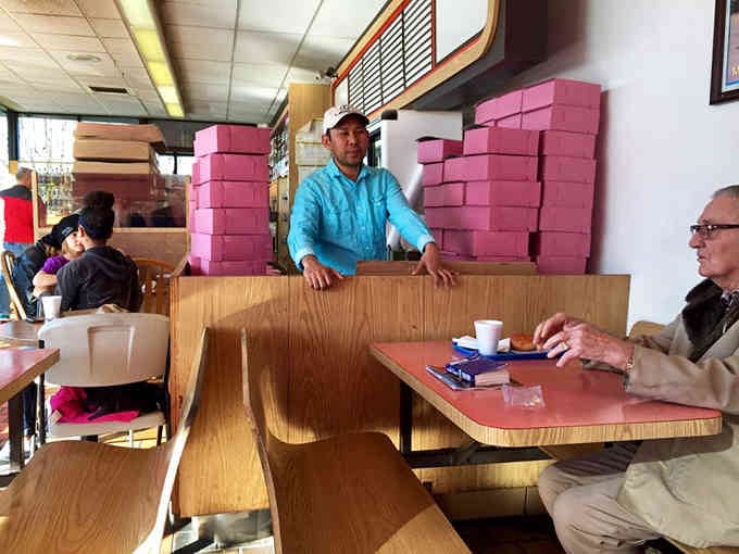 Those pink boxes stacked high signal serious donut business happening here, the kind that requires industrial-scale sweetness.