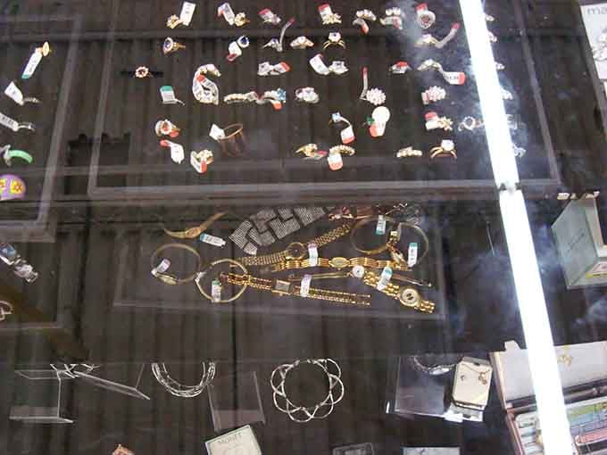 Jewelry sparkling behind glass, where someone's forgotten treasures become your statement pieces at fraction of original prices.