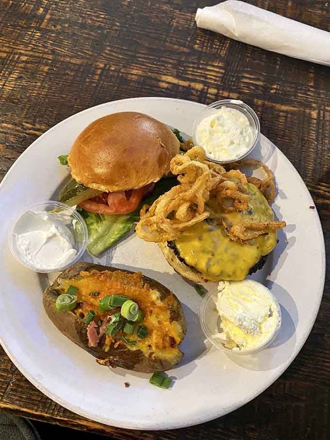 That burger comes with a loaded baked potato and onion rings, because apparently moderation took the day off.