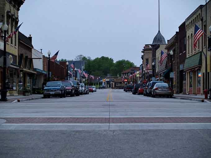 American flags line streets that have seen horse-drawn wagons transform into modern automobiles over the decades.