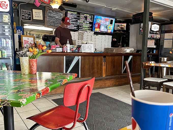 The ordering counter where pizza dreams begin, complete with cheerful flowers brightening your wait for culinary happiness ahead.