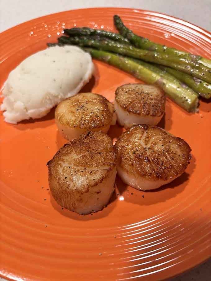 Seared scallops with that perfect golden crust, sitting pretty next to asparagus like edible works of culinary art.