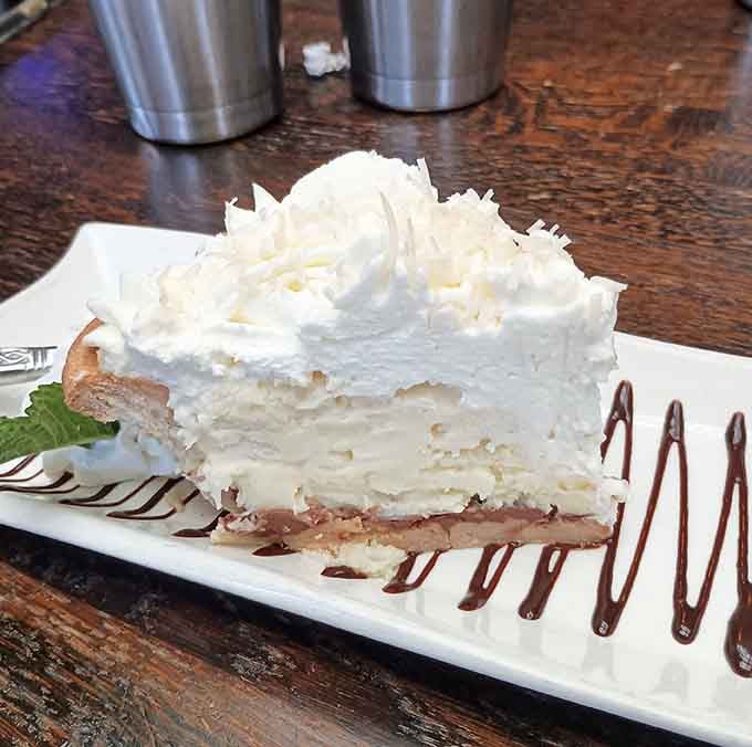 Coconut cream pie towering with meringue that defies gravity and common sense, in the best possible way imaginable.