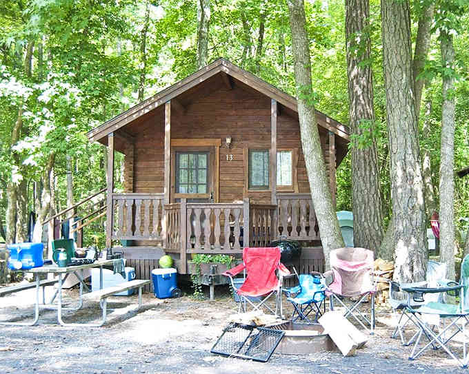 A cozy cabin surrounded by camping chairs, proving you can have both rustic charm and comfortable seating arrangements.
