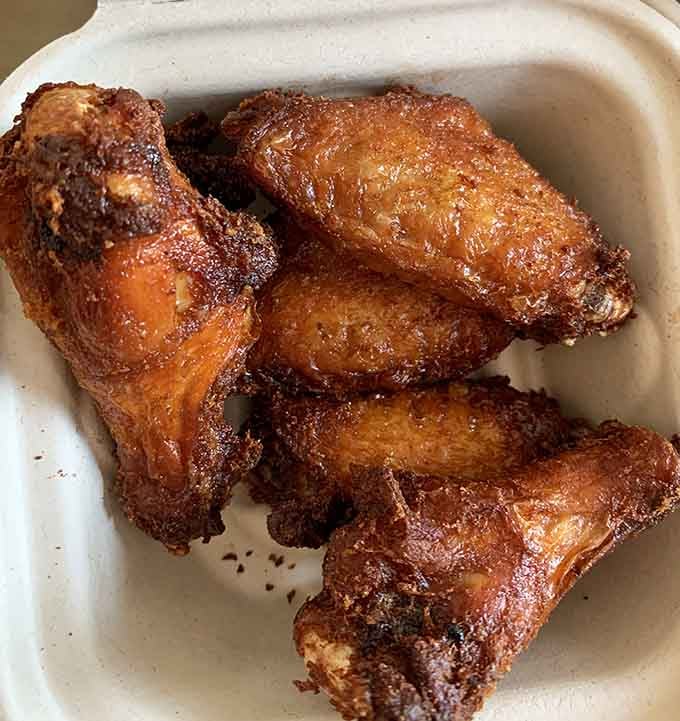 Chicken wings with that perfect caramelized exterior that suggests someone in the kitchen actually cares about your happiness today.