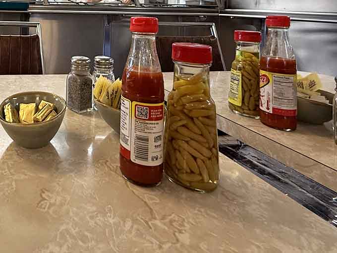 Hot sauce, peppers, and ketchup lined up like soldiers ready to enhance whatever deliciousness you've chosen today.
