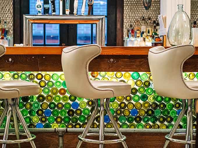 The bar features creative seating backed by colorful glass bottles, creating an artistic focal point that's both functional and beautiful.