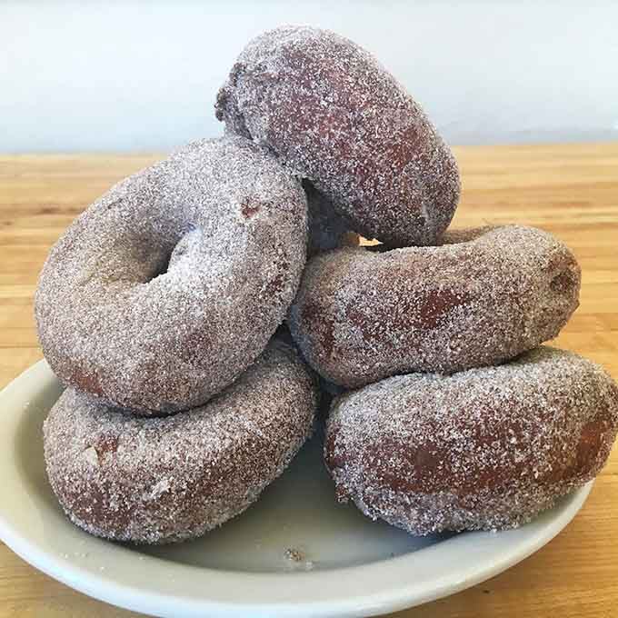 Sugar-dusted spudnuts stacked high, making potato-based donuts look like the genius invention they truly are.