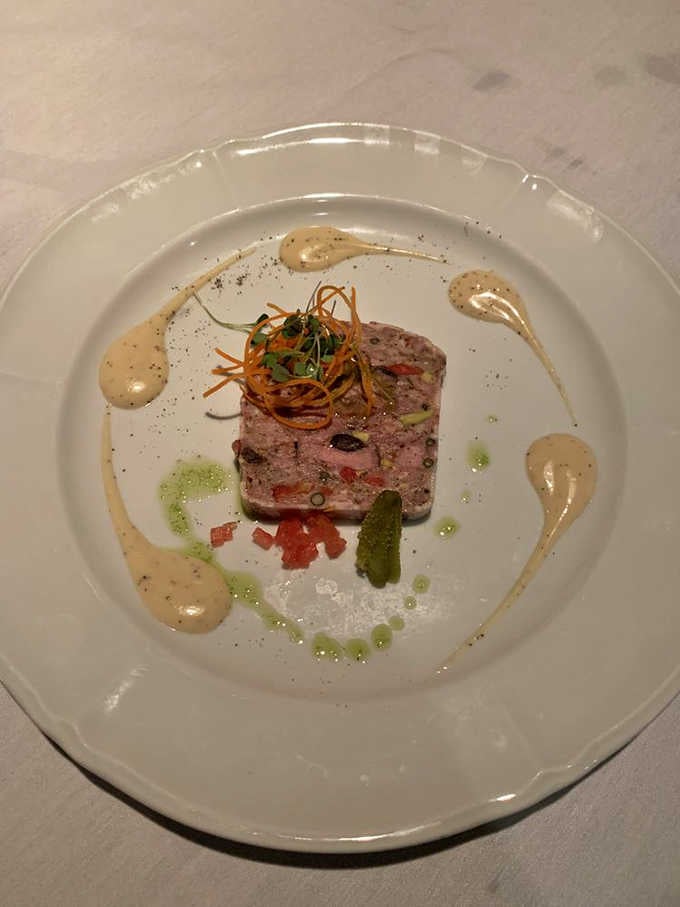 French country terrine presented with artistic sauce swirls that prove food can absolutely be art without being pretentious about it.