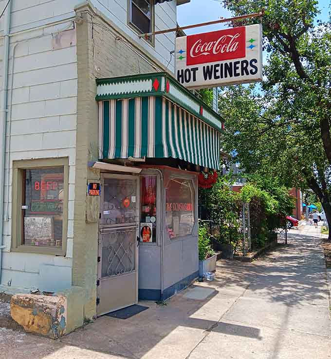 A tiny storefront with a big Coca-Cola sign, standing proud on a downtown street like it owns the place.