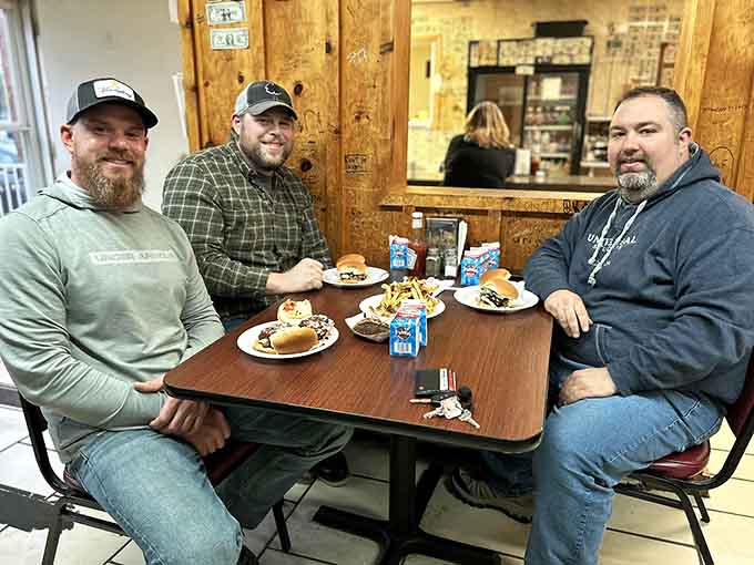 Three happy customers enjoying their burgers at a simple table&mdash;proof that great food brings people together beautifully.