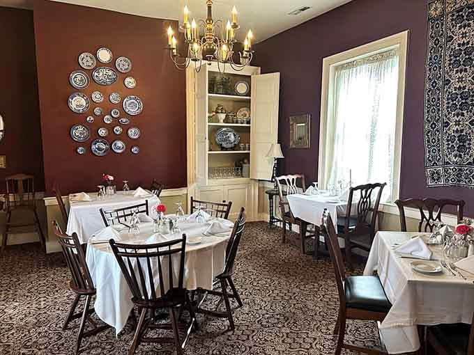 Rich burgundy walls and decorative plates create an atmosphere where every meal feels like a celebration.