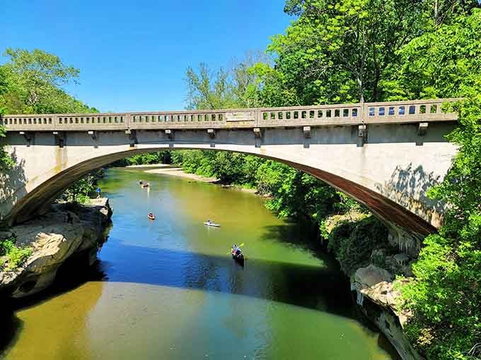 Kayakers glide beneath elegant arches while the creek mirrors endless blue skies in waters surprisingly clear and inviting.