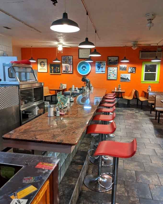 Orange walls and pendant lights create a warm, inviting atmosphere that feels like your coolest aunt's kitchen from 1972.