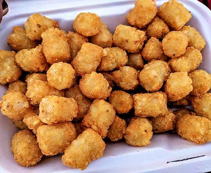 Golden tater tots piled high like edible treasure, crispy on the outside and fluffy within, pure joy.